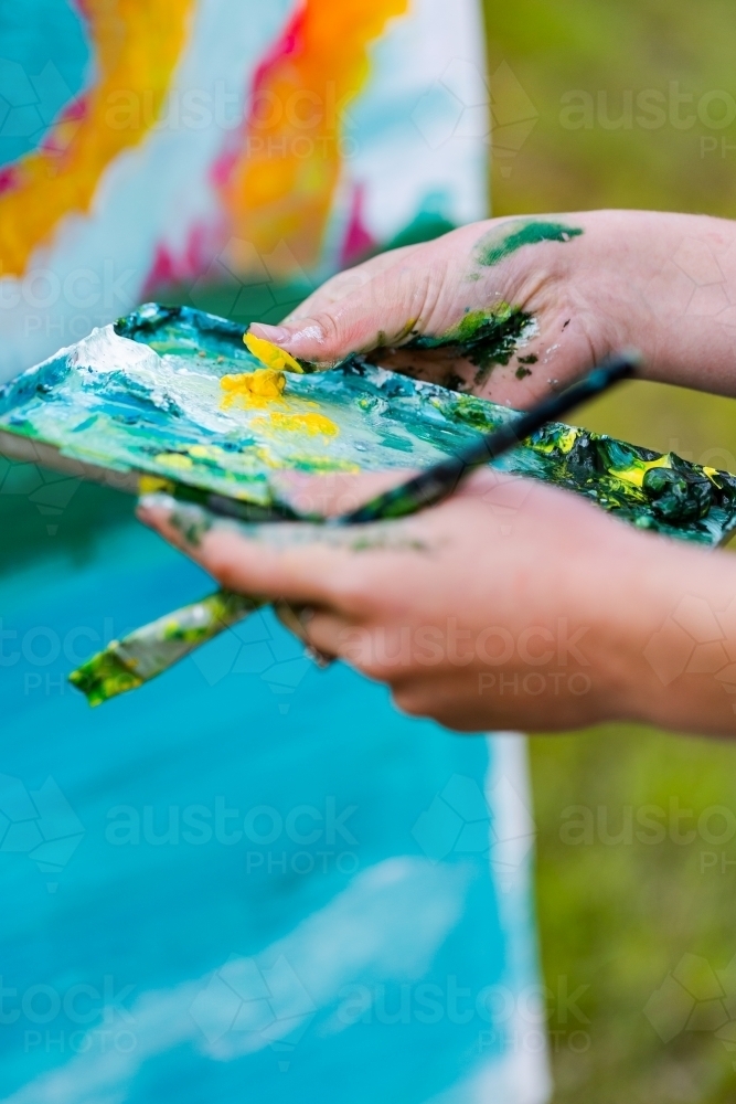 Image of Artists hands mixing paint colours on palette - Austockphoto