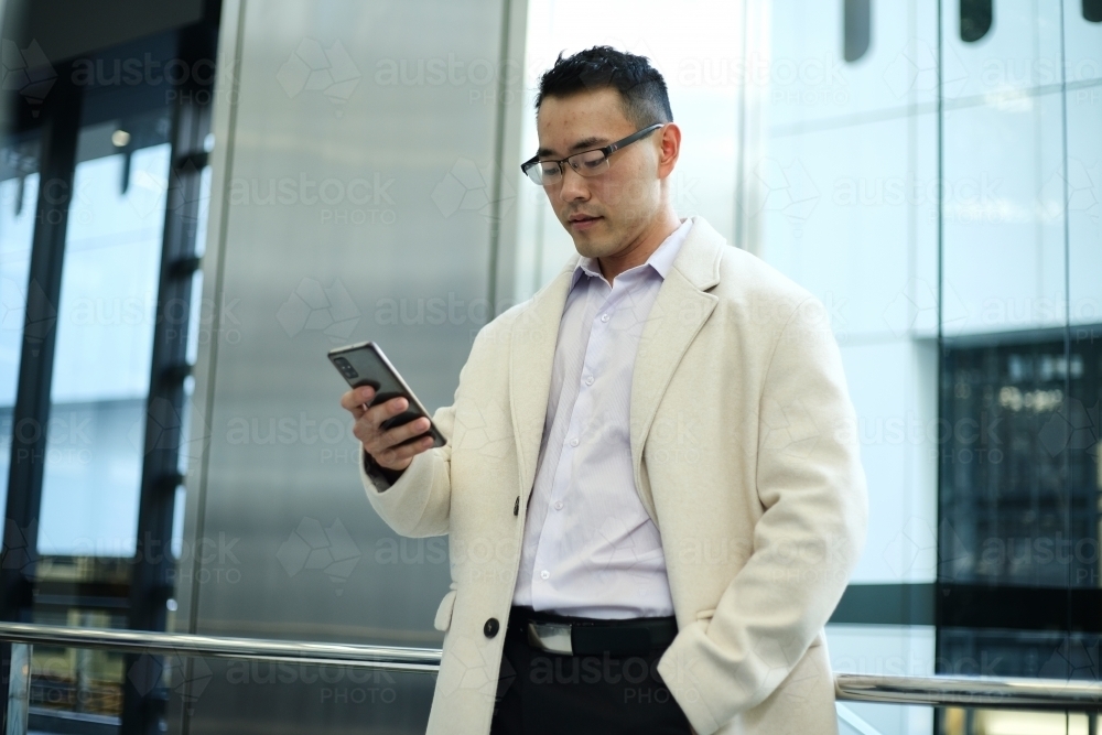Image of Asian businessman wearing cream coat in modern workplace ...