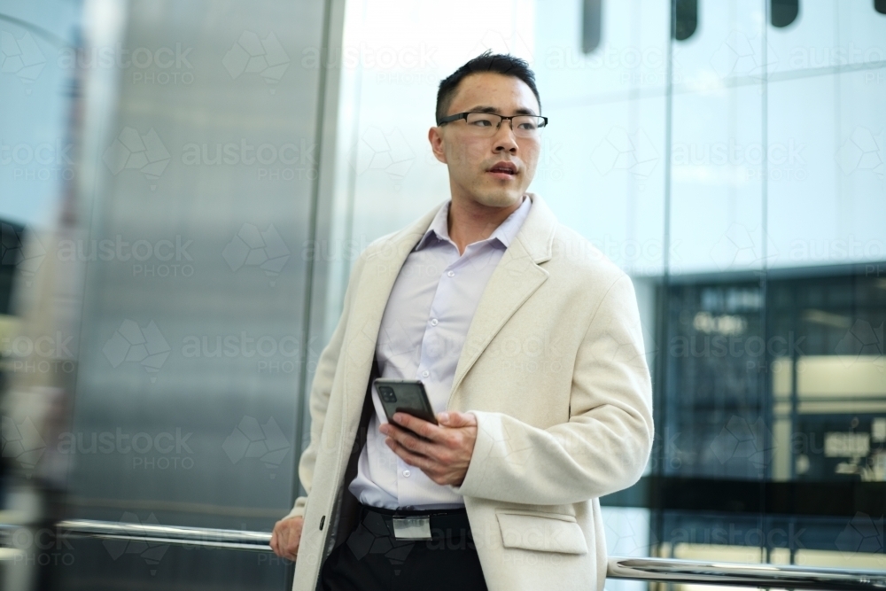 Image of Asian businessman wearing cream coat in modern workplace ...