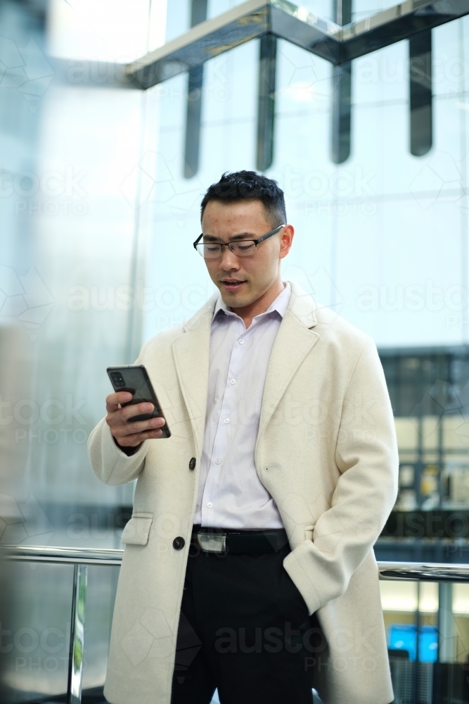 Image of Asian businessman wearing cream coat in modern workplace ...