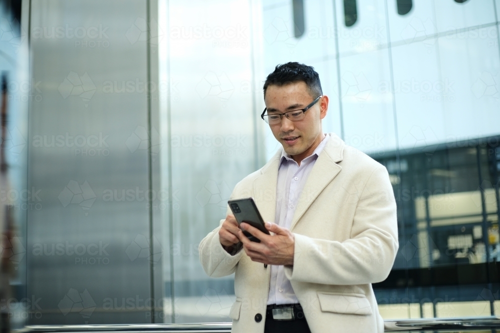 Image of Asian businessman wearing cream coat in modern workplace ...