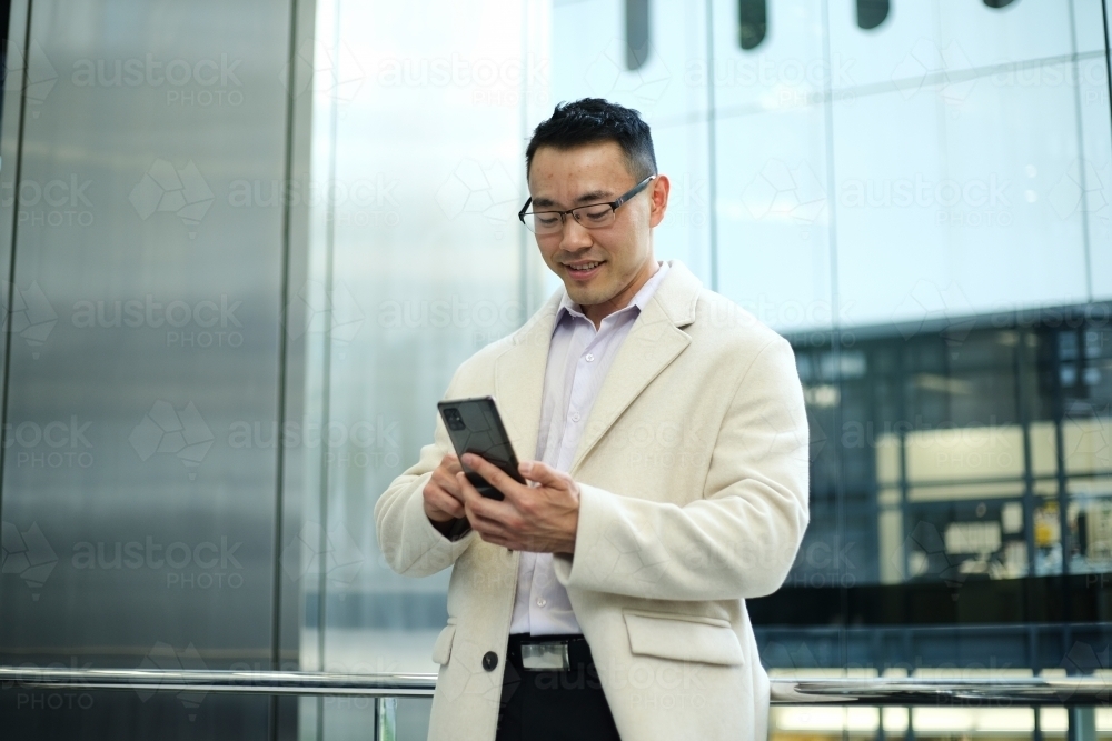 Image of Asian businessman wearing cream coat in modern workplace ...
