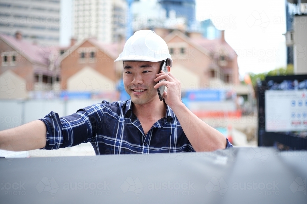 Image of Asian man at work on a call - Austockphoto