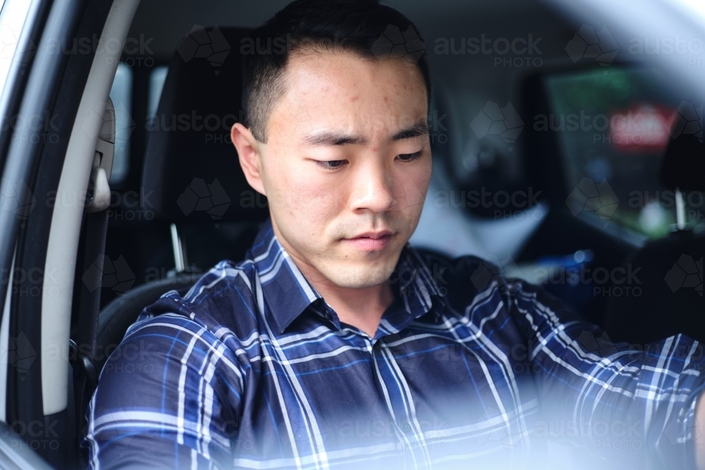 Image of Asian man in driver's seat of car - Austockphoto