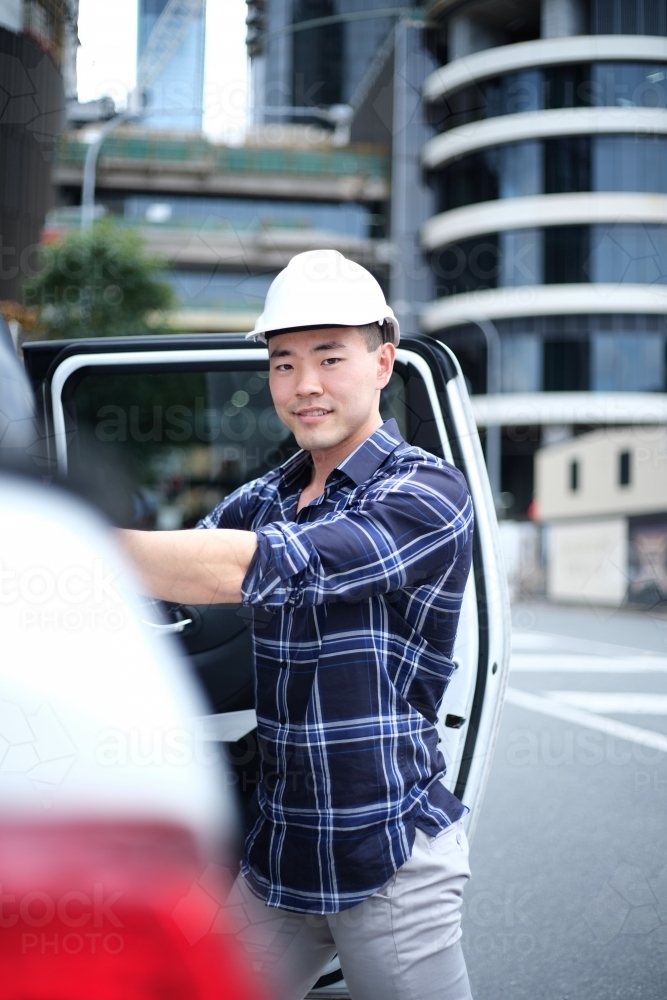 Image of Asian man with hard hat getting into car - Austockphoto
