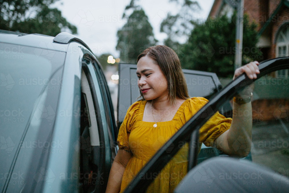 Image of Asian woman getting into car. - Austockphoto