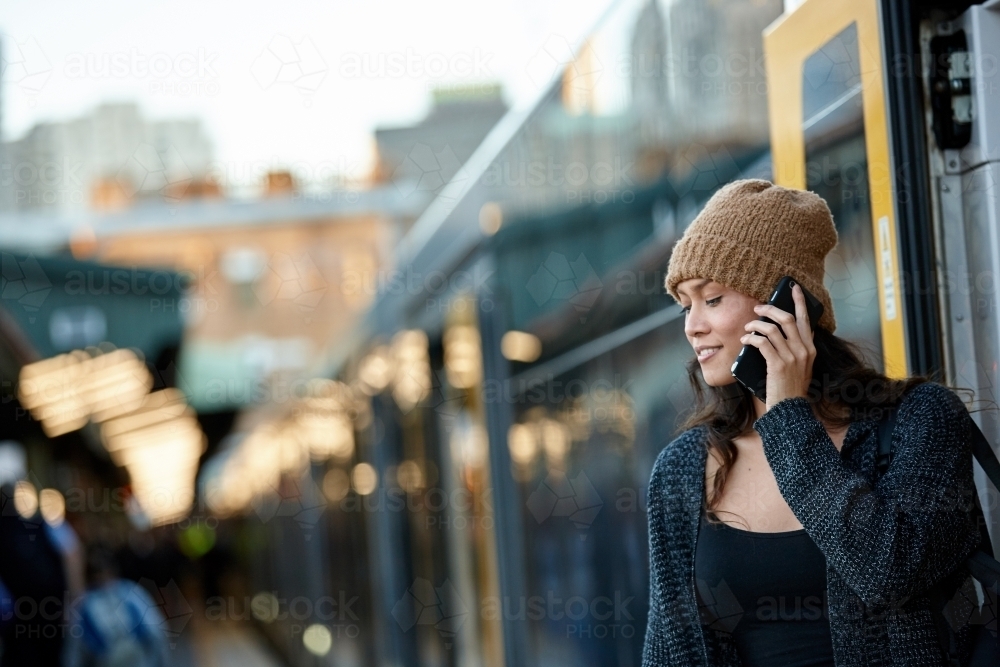 Image of Asian woman getting off train at station talking on mobile ...