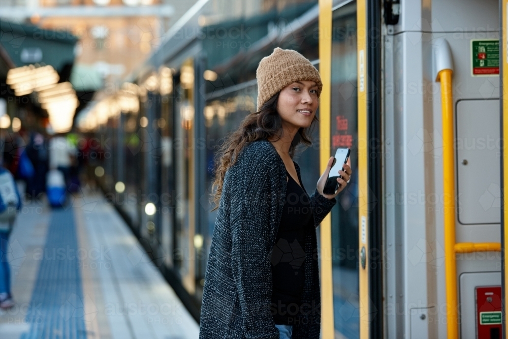 Image of Asian woman getting on train with mobile phone - Austockphoto