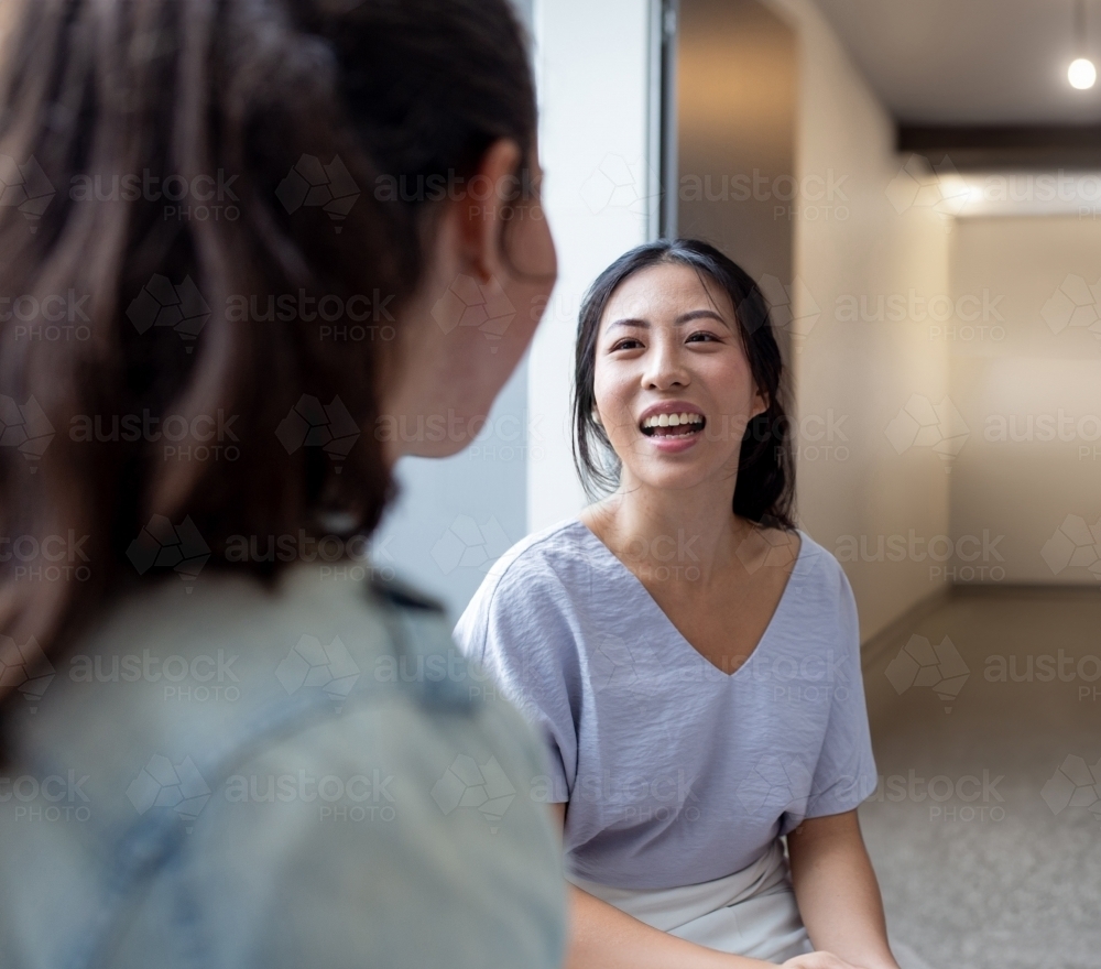 Image of Asian woman smiling while talking to her colleague in an ...