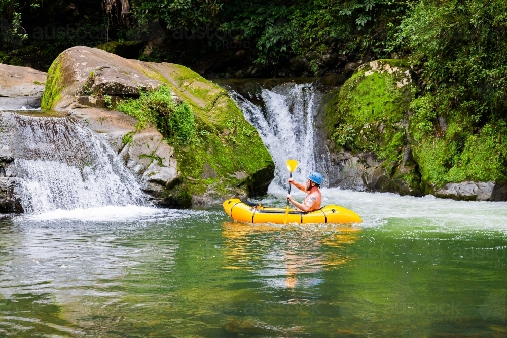 Image of Aussie adventurer paddling down mountain stream in inflatable ...