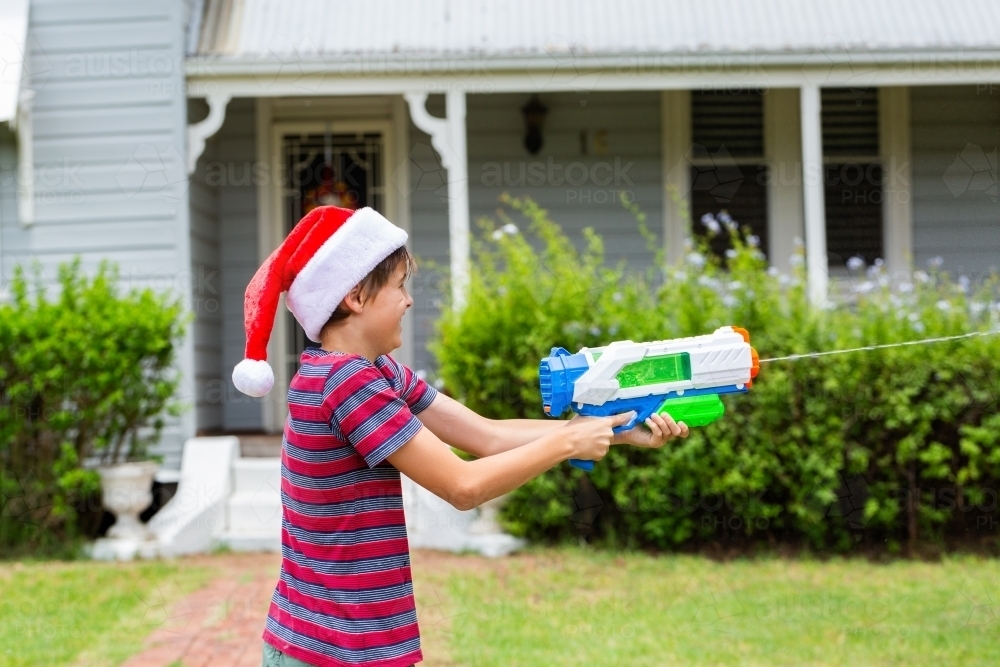 Image of Aussie boy in Christmas Santa hat squirting water gun ...