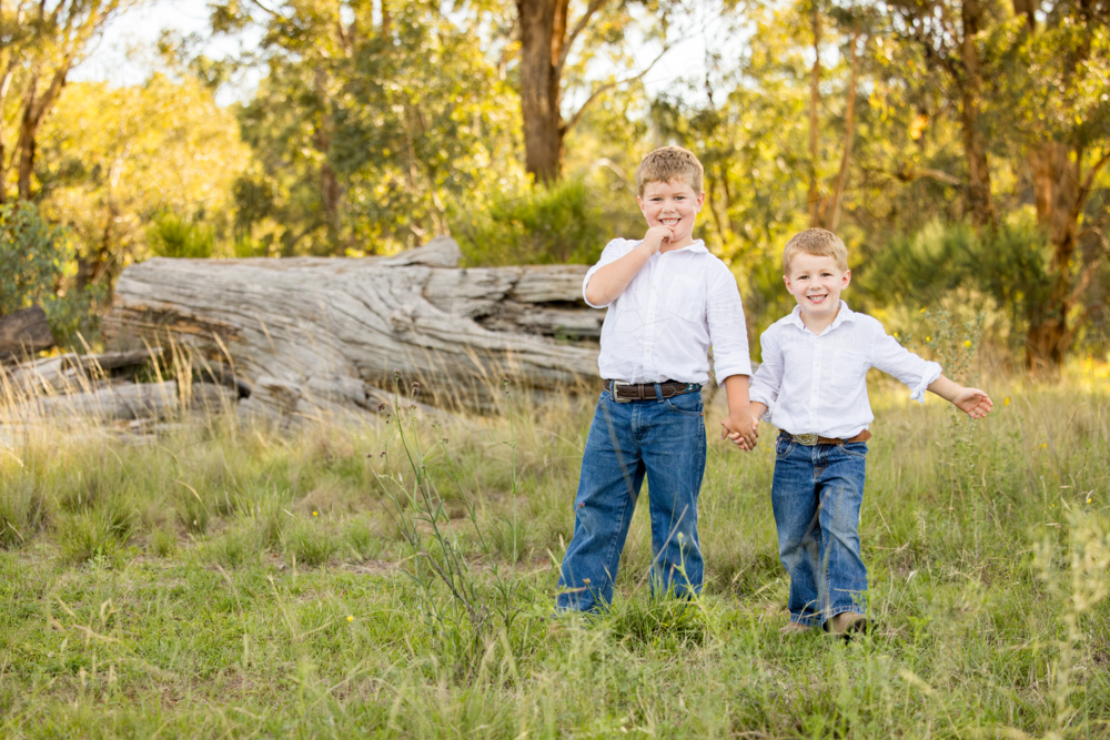 Image of Aussie brothers holding hands in lush green field - Austockphoto