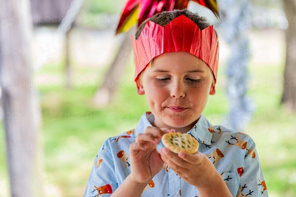 Image of Aussie child staring hungrily at fruit mince pie in hands ...