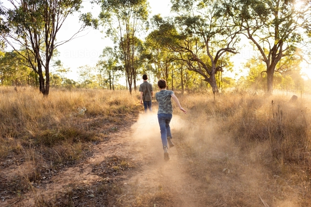 Image of Aussie country kids running through dusty paddock in rural ...