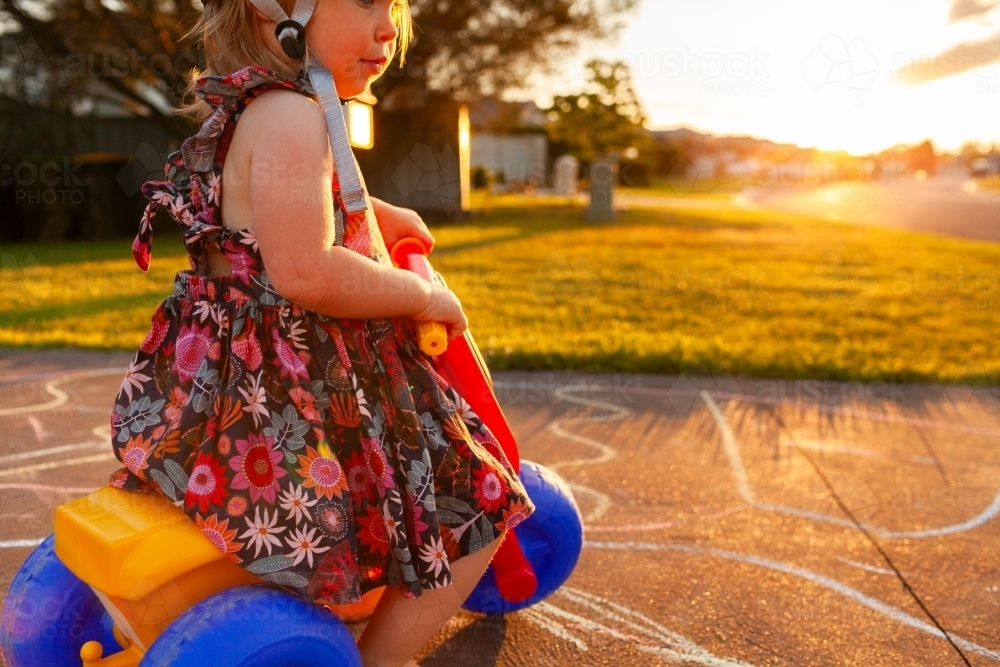 Image of Aussie kid on trike riding on chalk path on suburban driveway ...