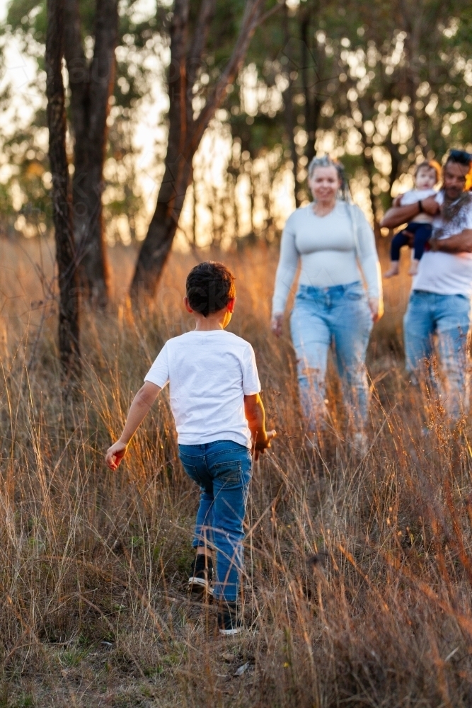 Image of Aussie kid running towards family in paddock while on bushwalk ...