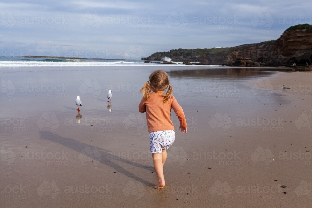 Image of Aussie kid running towards seagulls on the beach on winters ...