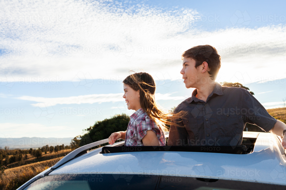 Image of Aussie kids looking out sunroof of family car parked on ...