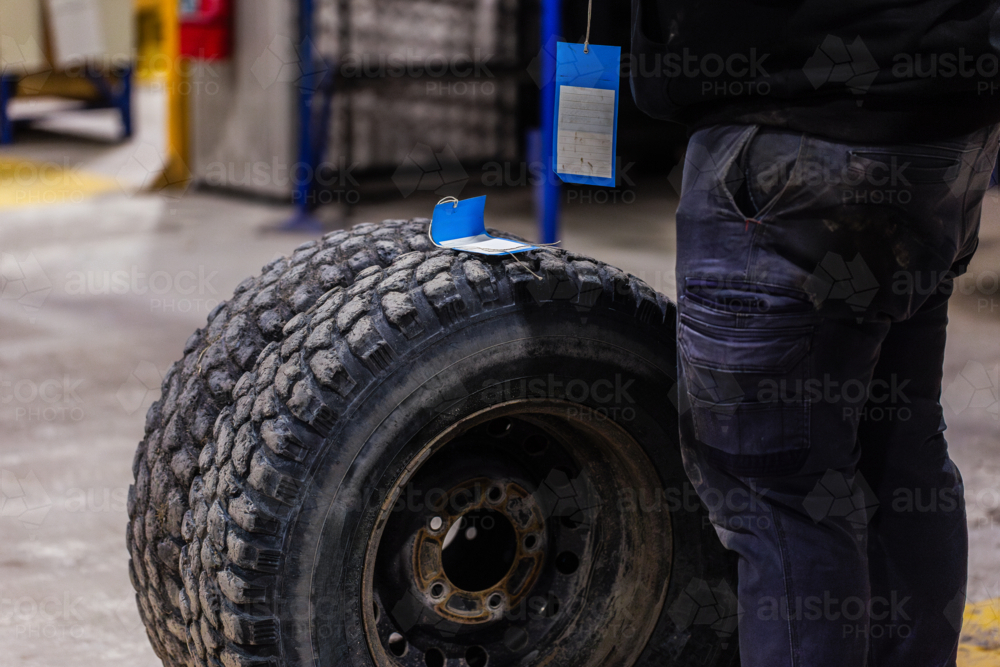 Image of Aussie mechanic standing beside rugged tire in an industrial ...