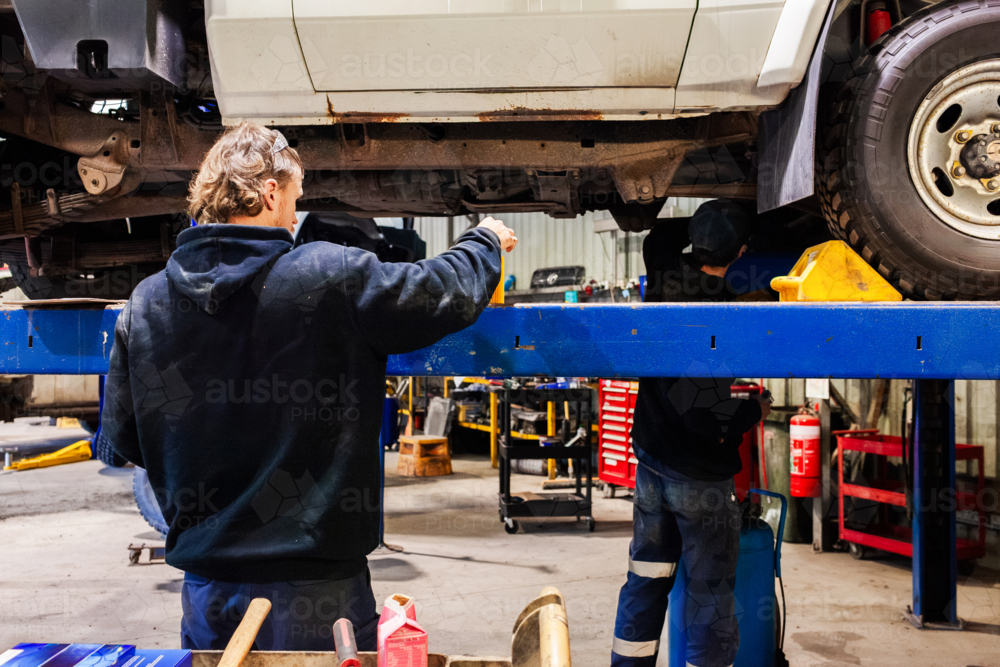 Image of Aussie mechanics working on the underside of white utility ...