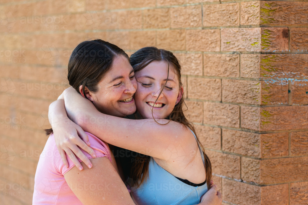 Image of Aussie mother and her teen daughter hug and smile together ...
