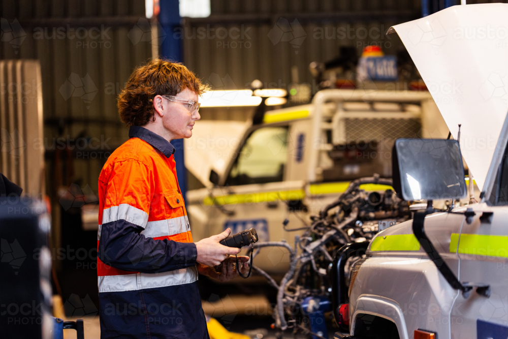Image of Aussie workman using digital diagnostics tool working on car ...