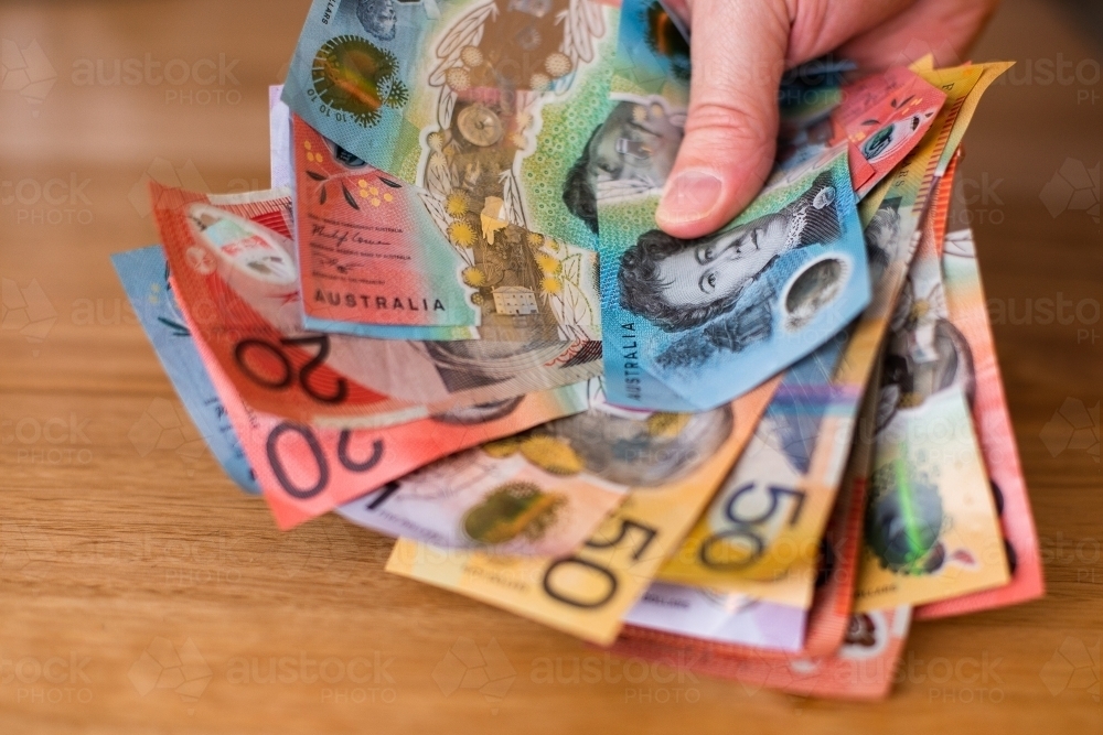 Image of Australian bank notes fanned out in a hand - Austockphoto