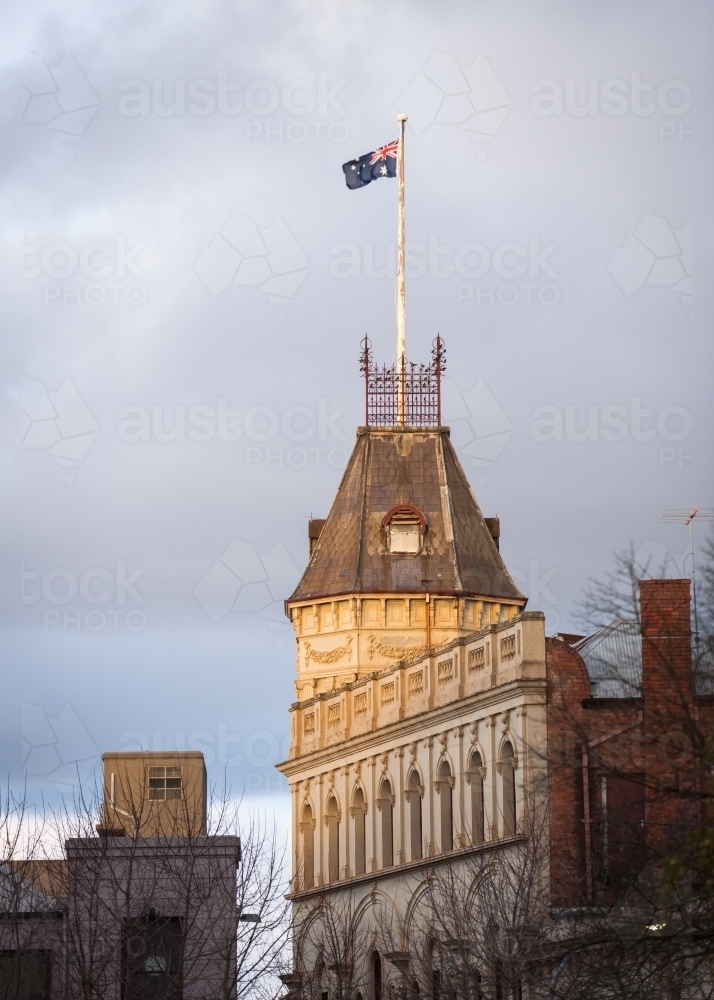 Image of Australian flag flying above a heritage building - Austockphoto
