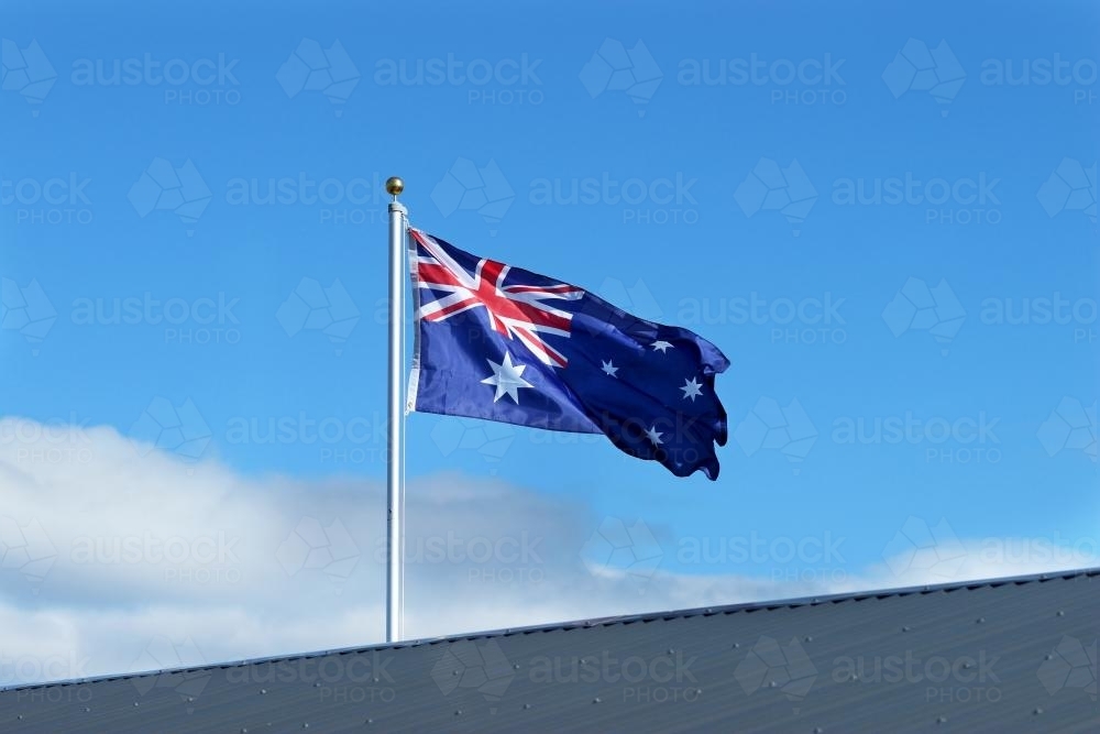 Image of Australian flag flying over the roof of a building - Austockphoto