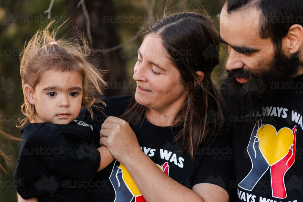 Image of Australian mum and dad standing holding unsure toddler girl ...