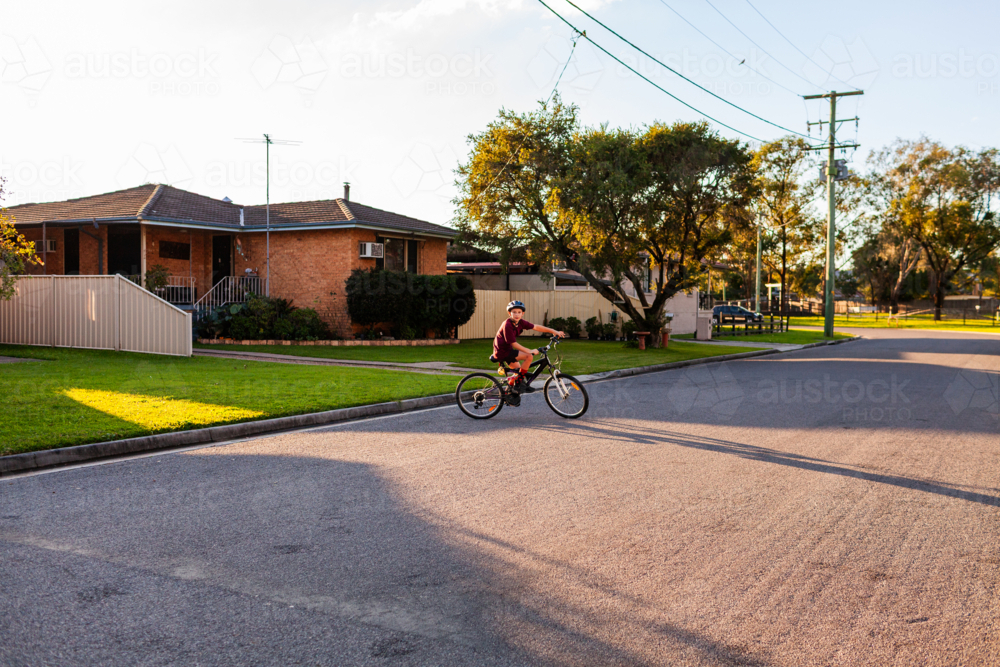 Image of Australian street scene with boy riding past on bike ...