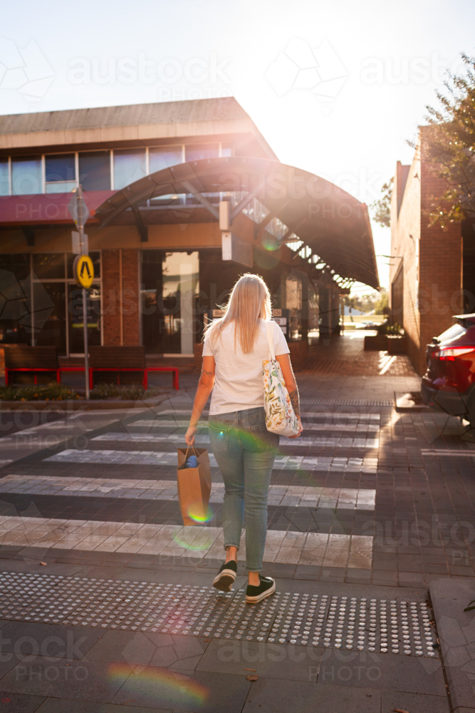 Image of Australian woman walking away down street over zebra crossing ...