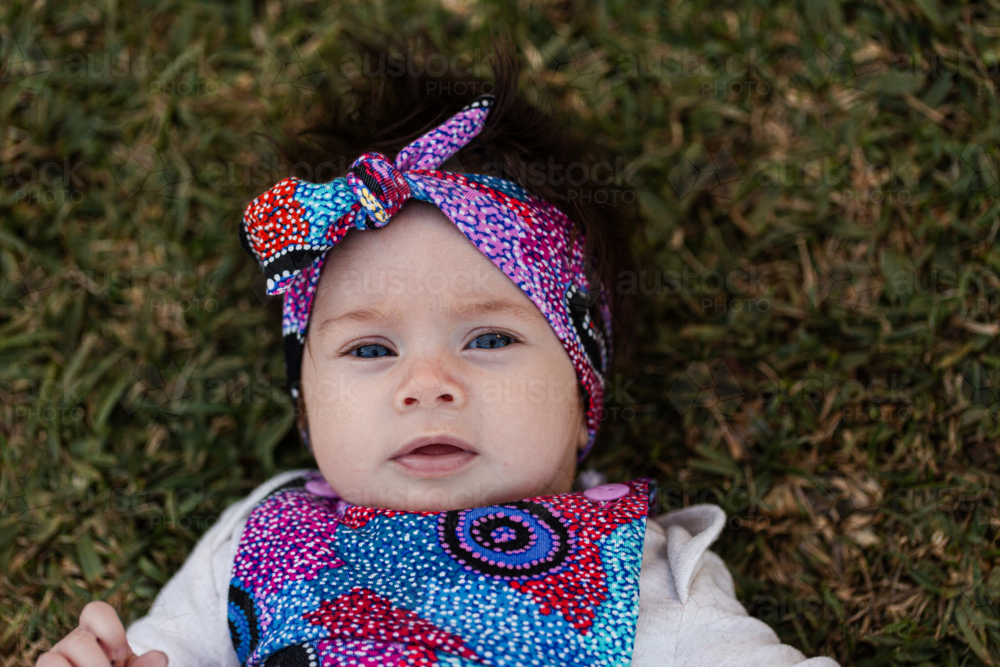 Image of Baby aboriginal girl lying on grass outside enjoying nature ...