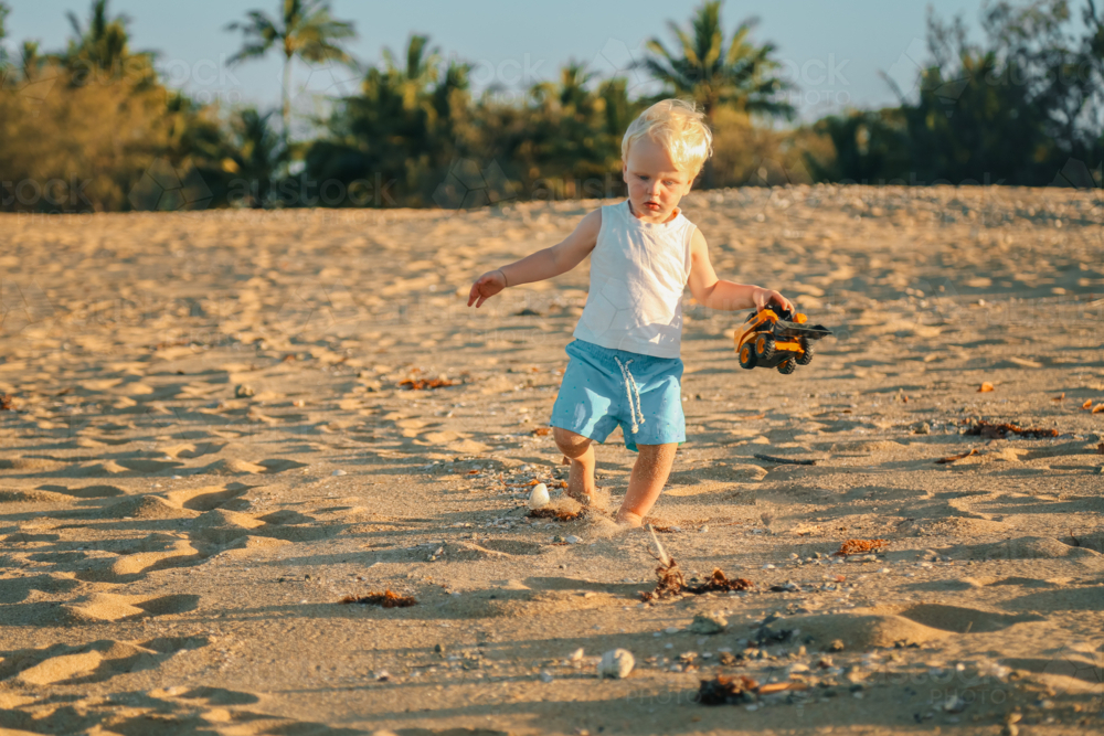 Image of Baby boy playing with digger in the sand at the beach ...