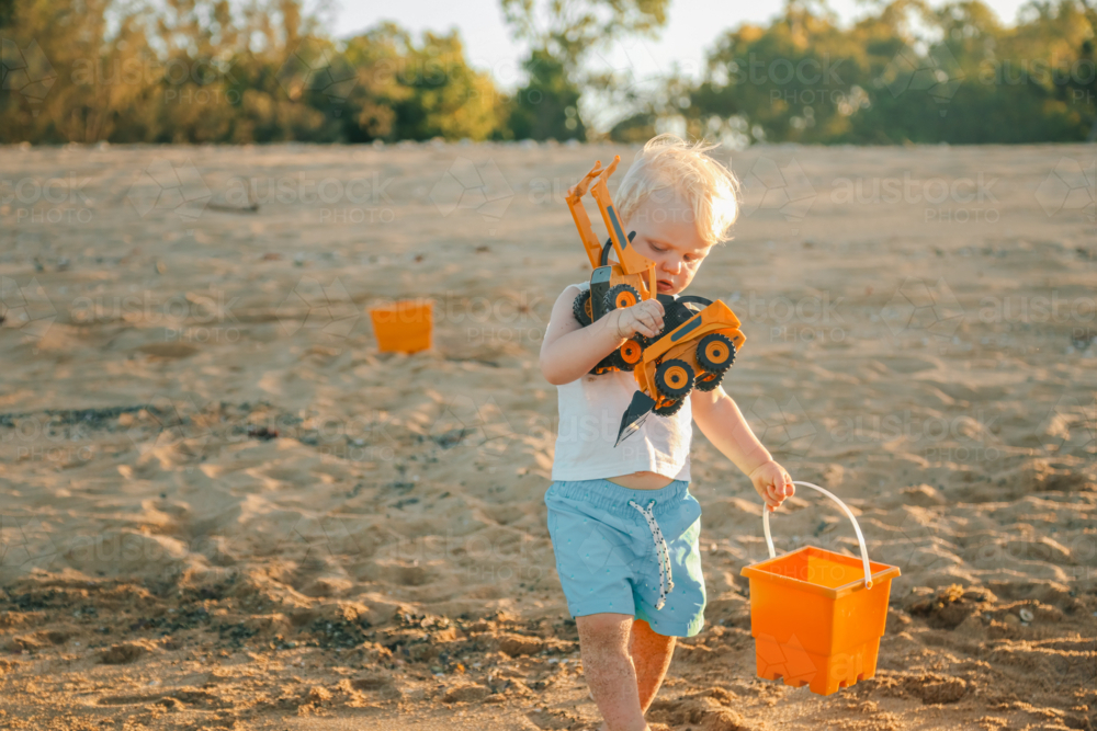 Image of Baby boy playing with diggers in the sand at the beach ...