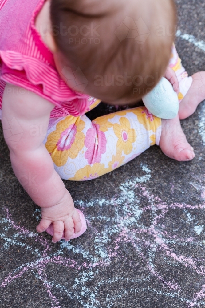 Image of Baby drawing with chalk on concrete - childhood - Austockphoto