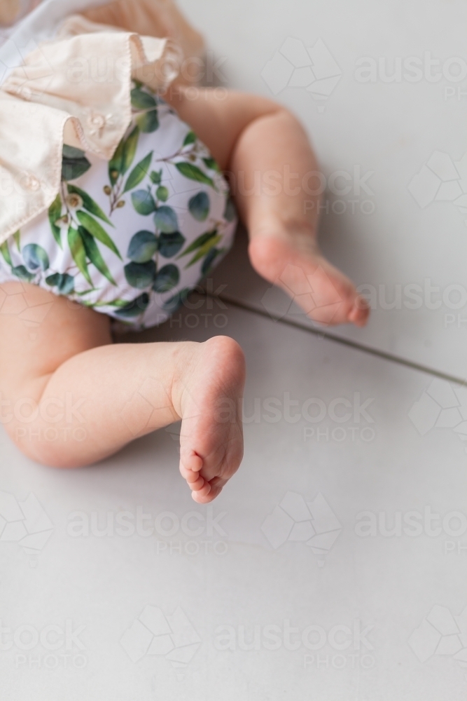 Image of Baby feet and nappy of crawling child on tiles - Austockphoto