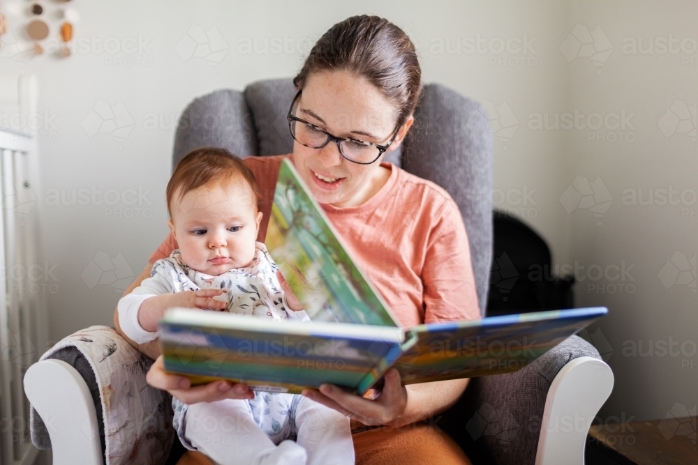Image of baby girl helping mum turn book pages as they read a story ...
