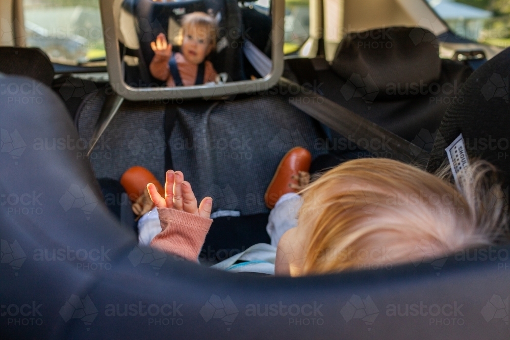 Image of Baby girl in car seat ready for road trip waving goodbye ...