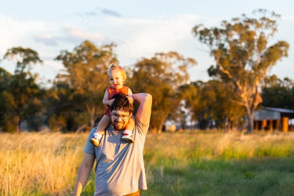 Image of Baby girl on dads shoulders riding piggyback through farm ...