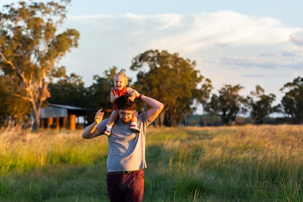 Image of Baby girl on dads shoulders riding piggyback through farm ...
