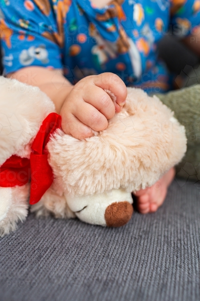 Image of Baby hand holding onto plush toy teddy bear ear - Austockphoto