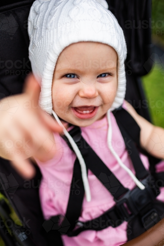 Image of baby in pram pointing at camera with cheeky expression ...
