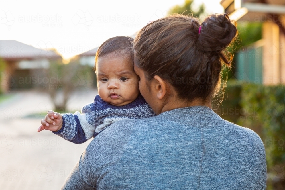 Image of Baby looking over his mother's shoulder - Austockphoto