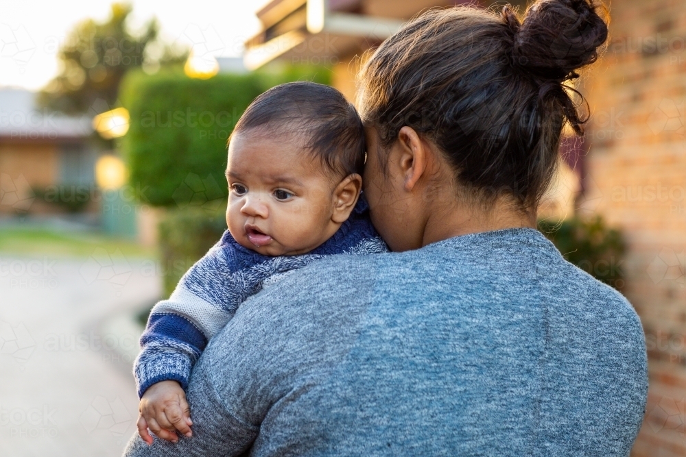 Image of Baby looking over his mother's shoulder - Austockphoto
