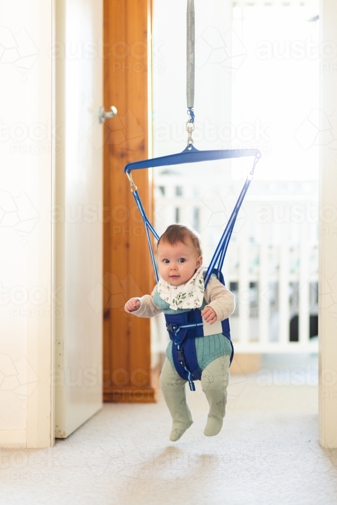 Image of Baby playing in jolly jumper bouncing toy in doorway ...
