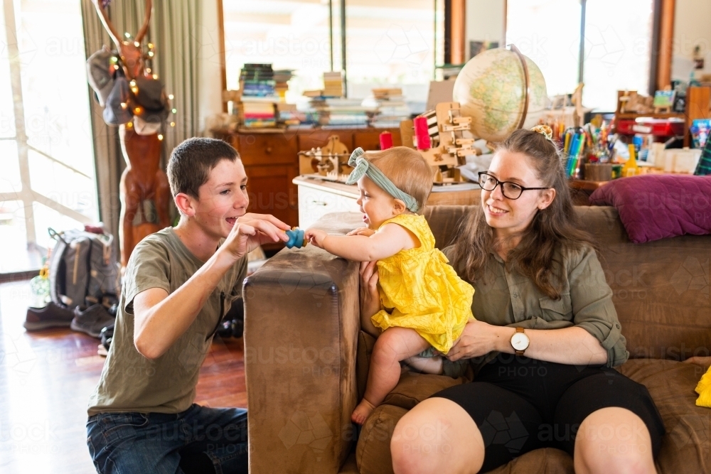 Image of baby playing with young uncle and aunty in home at Christmas ...