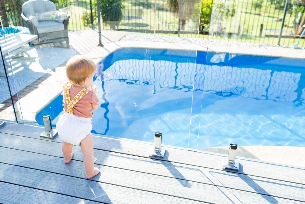 Image of Baby standing against glass fence of swimming pool in Aussie ...