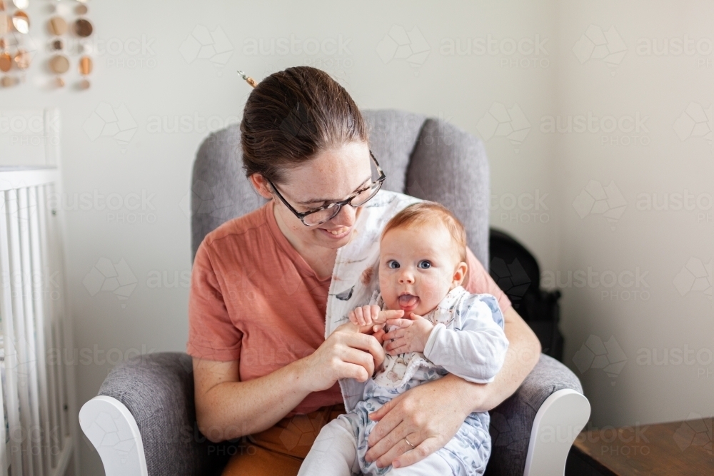Image of Baby trying to lick mums finger while cuddling together in ...