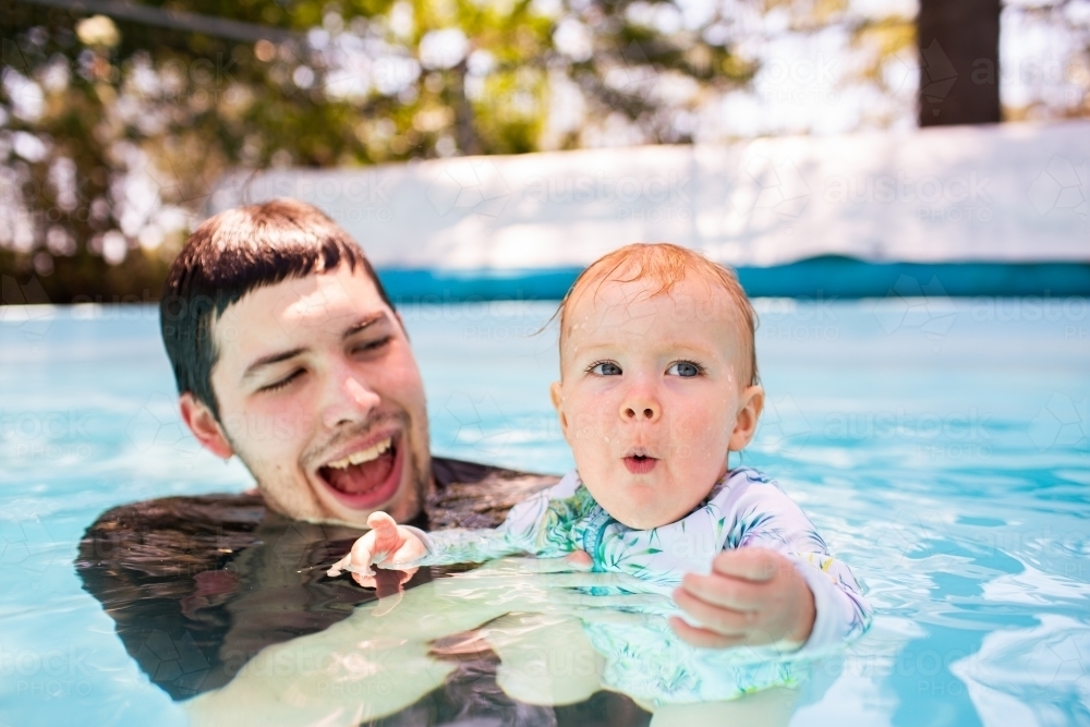 Image of baby with excited expression in swimming pool water with ...